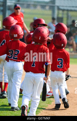 Little league baseball team players boy hits ball and runs to first ...