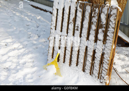 Yellow rake under snow in winter day Stock Photo - Alamy