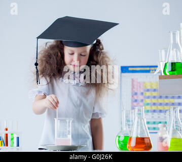 Cute scientist schoolgirl in lab coat looks through microscope for ...