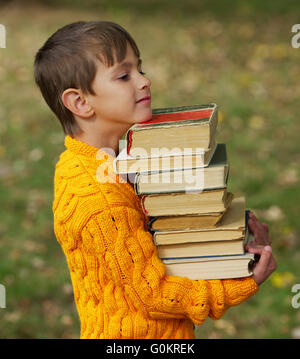 Cute cheerful child carrying stack of books Stock Photo - Alamy