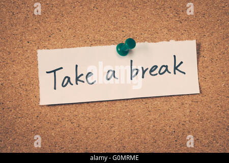 Paper note with the phrase Take a Break! on bulletin board. Close up ...