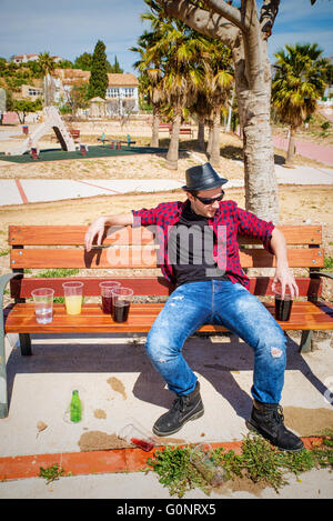 Guy getting heavily drunk on a park bench Stock Photo - Alamy