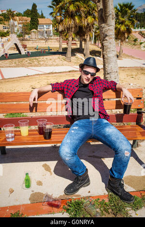 Guy getting heavily drunk on a park bench Stock Photo - Alamy