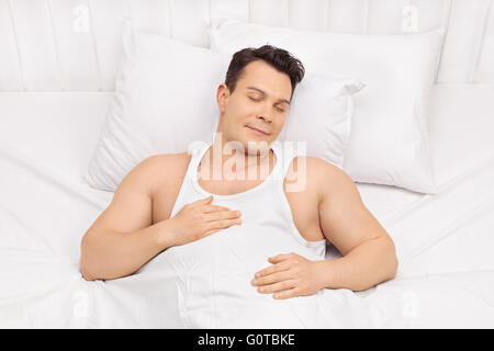 Young man sleeping on soft mattress against color background Stock ...