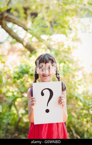 Child holding sheet of paper with question mark on black background ...