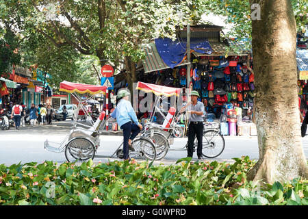 Vietnam rickshaw, two rickshaw drivers chat while taking their ...