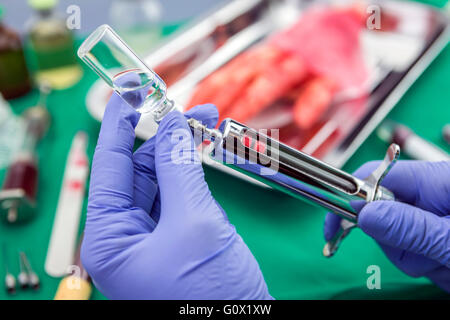 Nurse filling syringe with medication in a room of operating theater ...