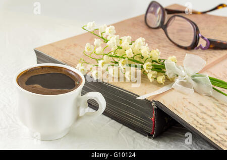 Beautiful lily-of-the-valley flowers, book and greeting card on light ...