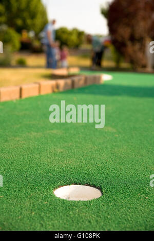 Cute, typical family playing outdoor mini-golf Stock Photo - Alamy