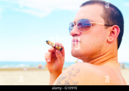 Guy smoking a cigar on the beach Stock Photo - Alamy