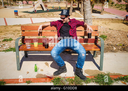 Guy getting heavily drunk on a park bench Stock Photo - Alamy