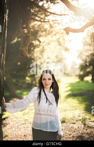 A happy woman with long dark hair, wearing a blue and white striped ...