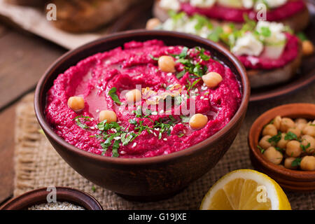 Hummus with beet in wooden bowl on a white wooden background and linen ...