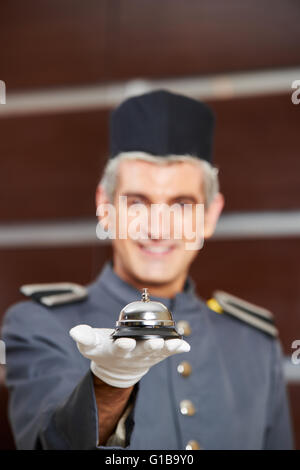 Hand of a concierge with a hotel bell Stock Photo - Alamy