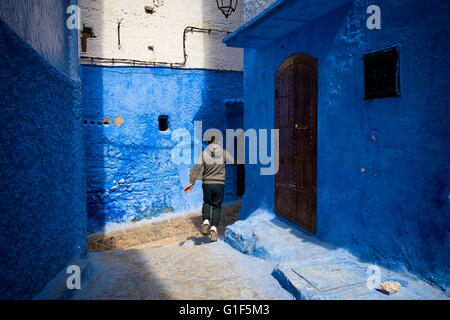 Kid playing in a street in Chefchaouen while a man is walking in the ...
