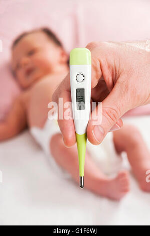 MODEL RELEASED. Taking baby's temperature. Sleeping 7-month-old baby ...