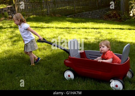 A little girl pulling a red wagon Stock Photo - Alamy