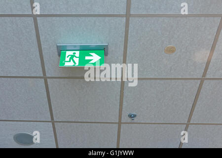 Standard international symbol safe exit sign is hanging from the ...