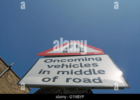 Road signs for road narrowing and oncoming vehicles in middle of road ...