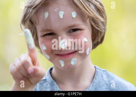 Little boy puts himself sunscreen on the face, sun protection Stock ...