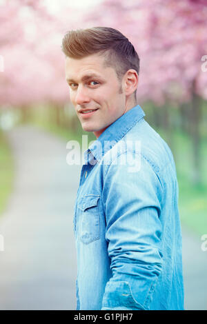 portrait of handsome man walking a path lined with cherry blossom Stock ...