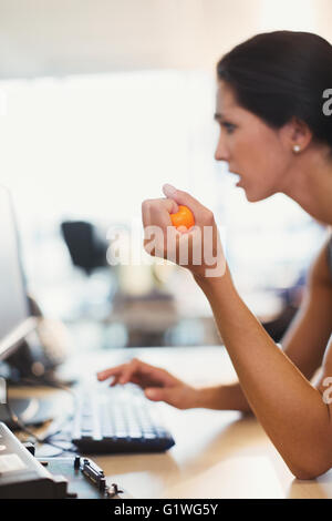 Woman squeezing stress ball while working in office Stock Photo - Alamy