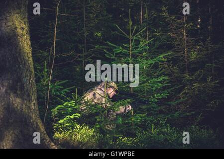 Camouflage Hunter or soldier hiding in bushes in camouflage autumn ...