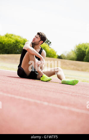 Tired athlete sitting on the running track Stock Photo - Alamy