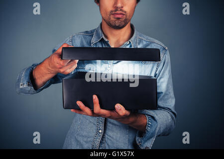 Young man opening a box with something exciting inside it Stock Photo ...