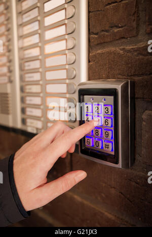 Woman dialing pass code on intercom security keypad to open entrance ...