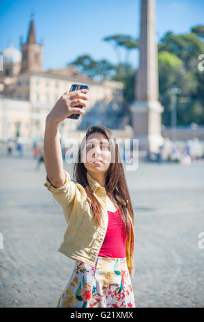 Pretty young woman taking selfie and showing victory gesture in bedroom ...