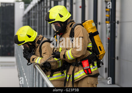 Firefighter wearing breathing apparatus ties a line from an external ...