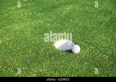 golf ball on lip of cup of lovely tropical golf course Stock Photo - Alamy