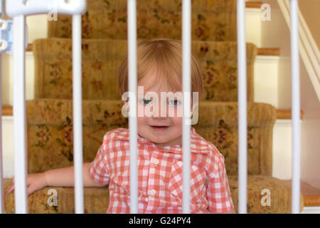 Toddler behind a baby gate Stock Photo - Alamy