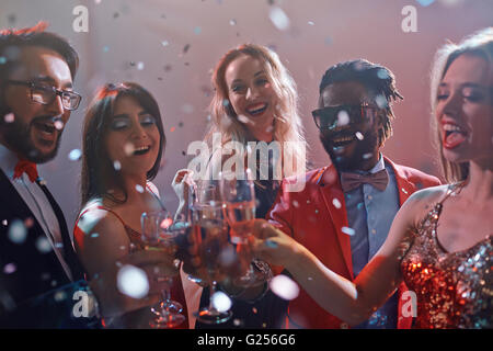 smiling young woman and man clinking glasses with red wine during ...