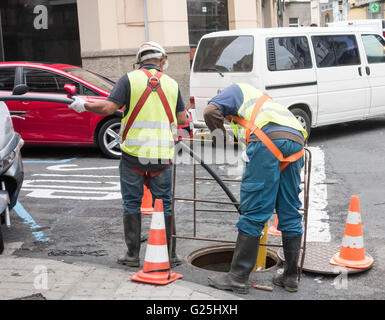 BT telephone engineers working in street and accessing underground ...