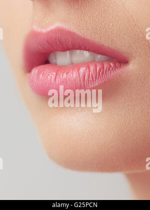 A young womans mouth, lips slightly parted showing teeth, close up ...