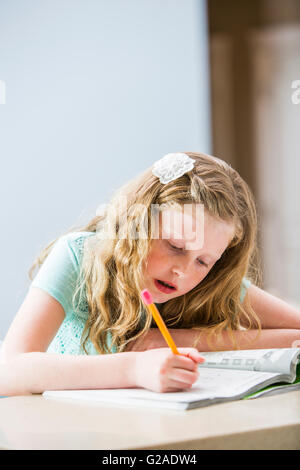 Schoolgirl with pencil writing down homework in exercise book Stock ...