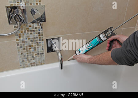 A workman uses a mastic gun to apply stone-coloured silicone sealant to ...