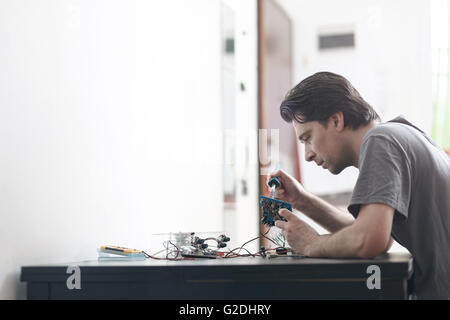 Young man making an electronic device soldering and adjusting the ...