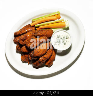 High angle of buffalo chicken wings with pepper sauce served with chips ...