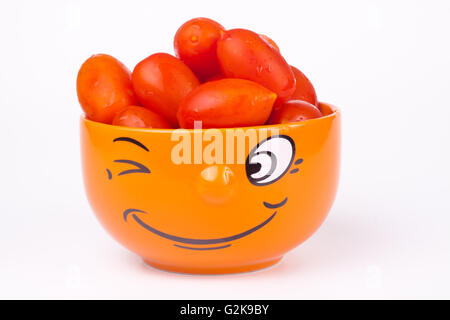 yellow smiley face bowl fullwith red cherry tomato isolated on white ...