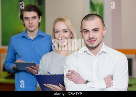 Team leader stands with coworkers in background Stock Photo - Alamy