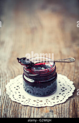 Spoon with plum jam on the retro decorated desk with fruit and glass ...
