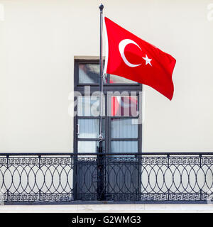 The Turkish national flag waving on a flagpole over the blue waters of ...