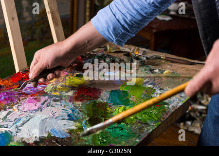 Artist's hand holding palette and brushes Stock Photo - Alamy