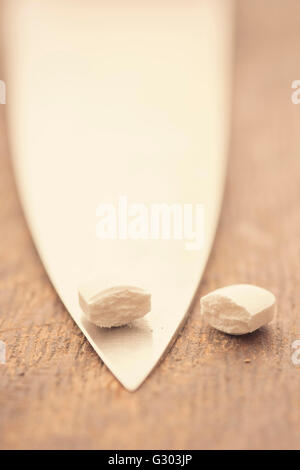 Medical capsule divided into two halves by large knife Stock Photo - Alamy