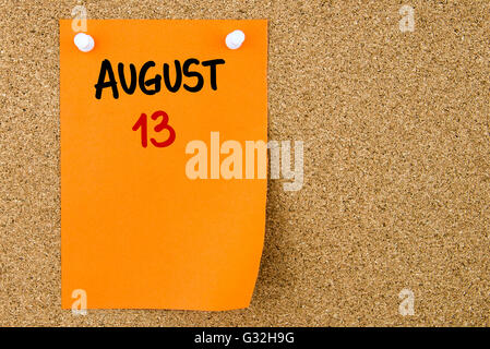 1 AUGUST written on orange paper note pinned on cork board with white ...