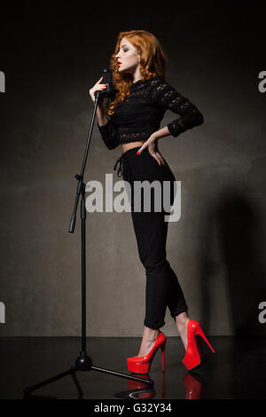 Portrait of red-haired woman signing in mic with wide-open mouth Stock ...