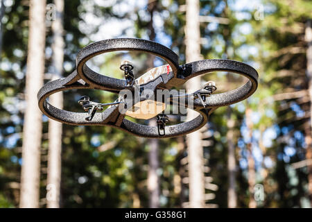 a small spy quad copter scout drone flying through the trees in a ...